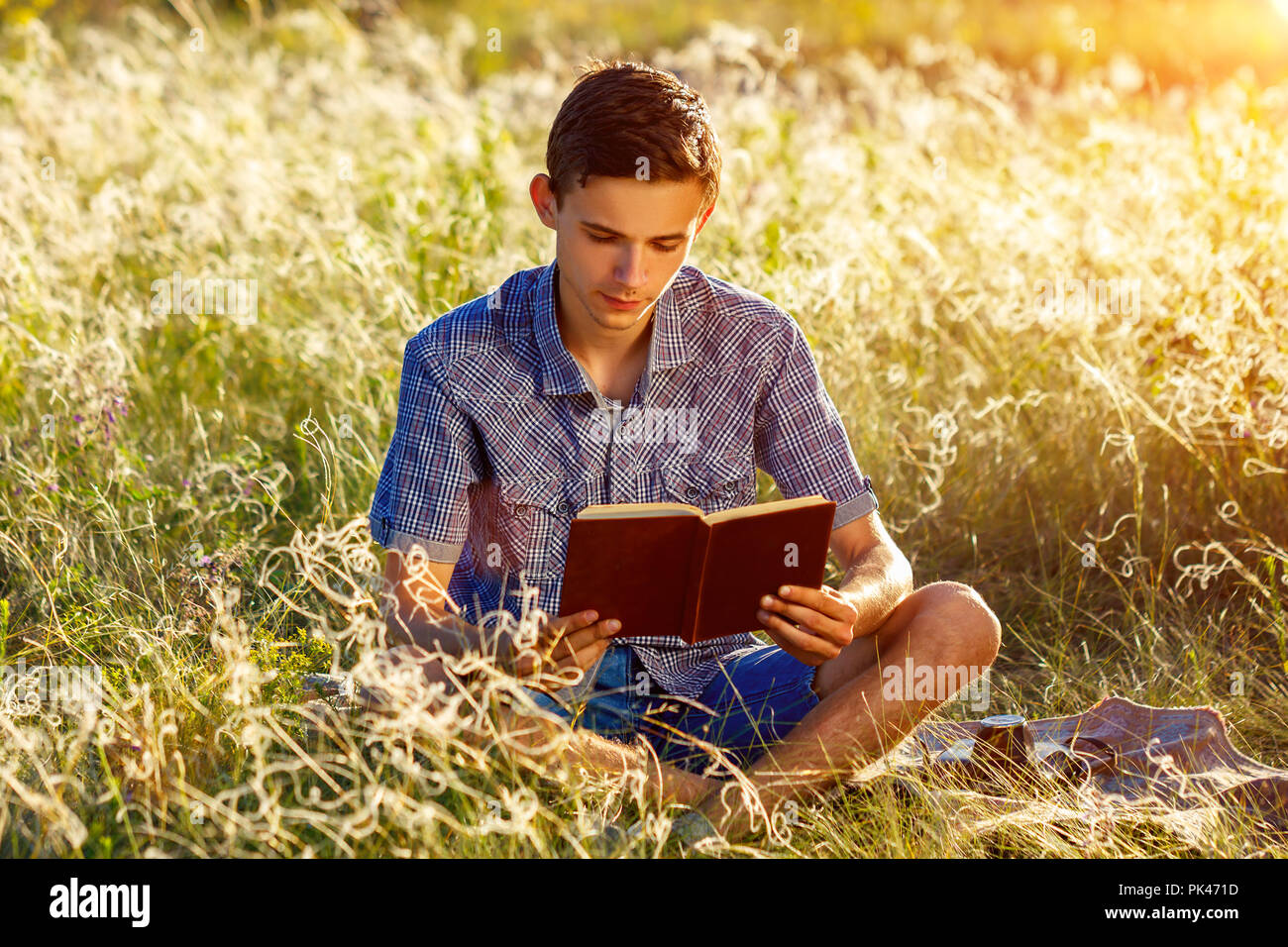 young man sitting in nature reading a book Stock Photo - Alamy