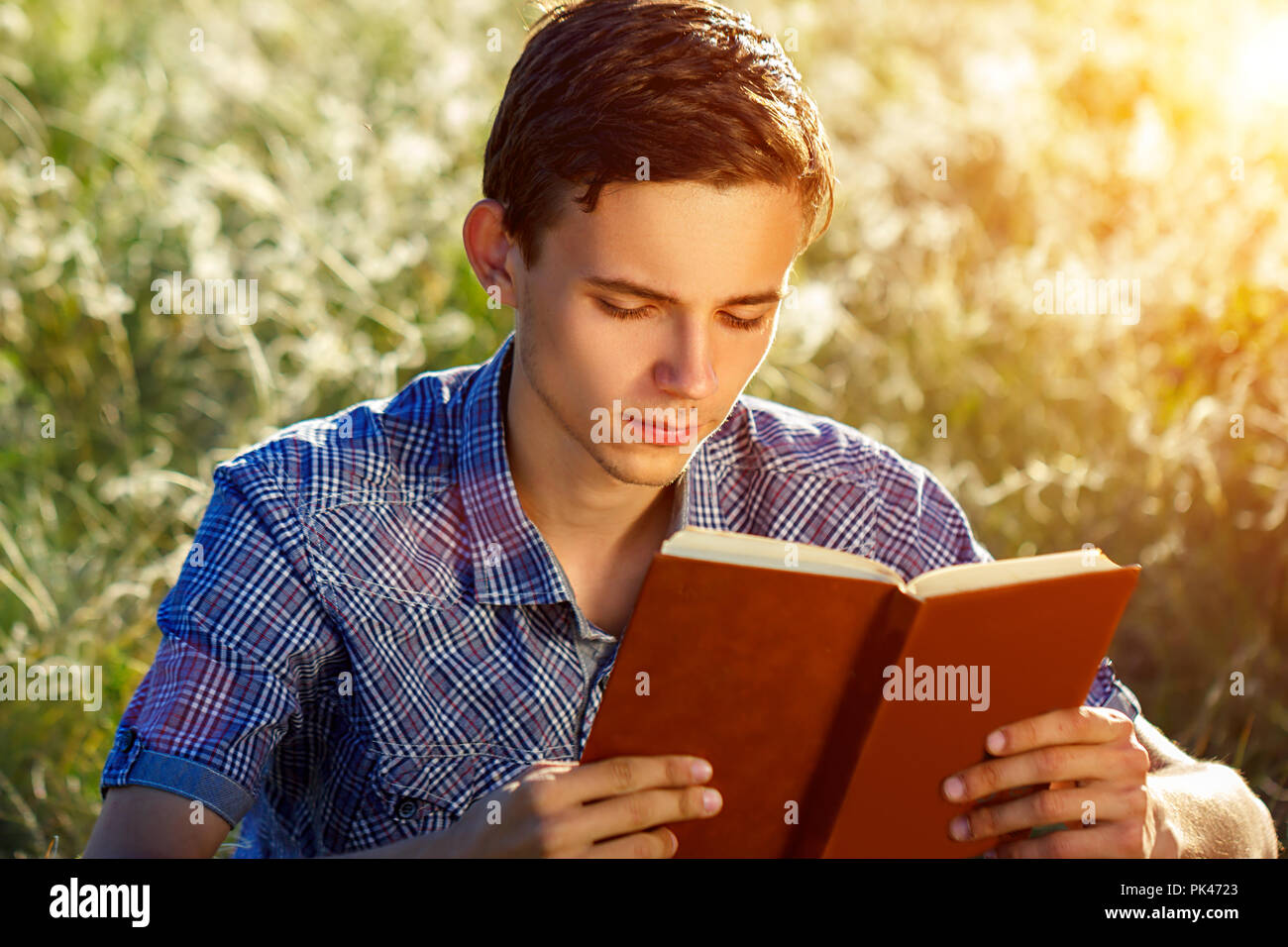 young man sitting in nature reading a book Stock Photo - Alamy