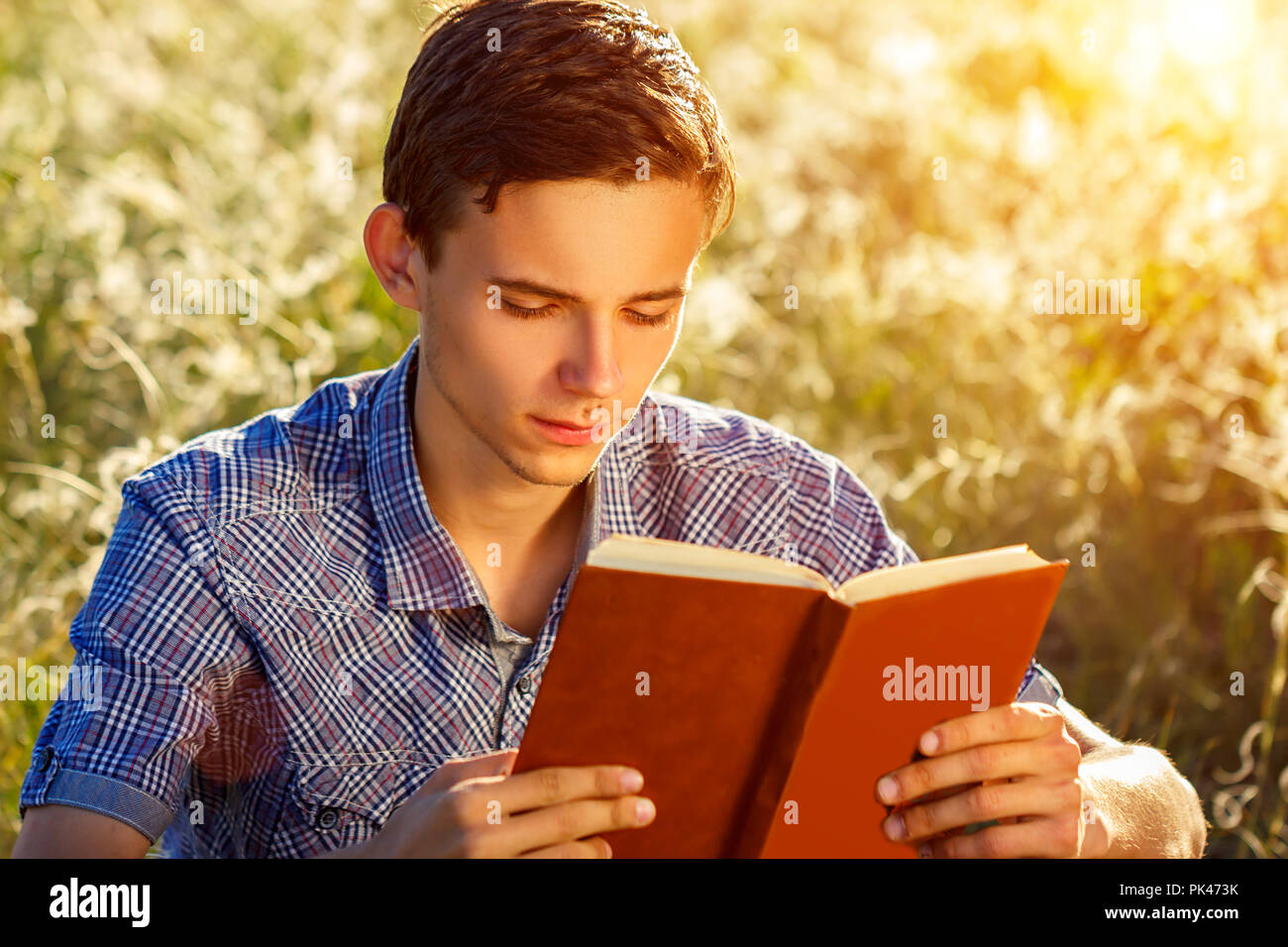young man sitting in nature reading a book Stock Photo - Alamy