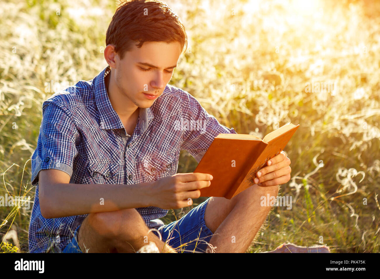 young man sitting in nature reading a book Stock Photo - Alamy