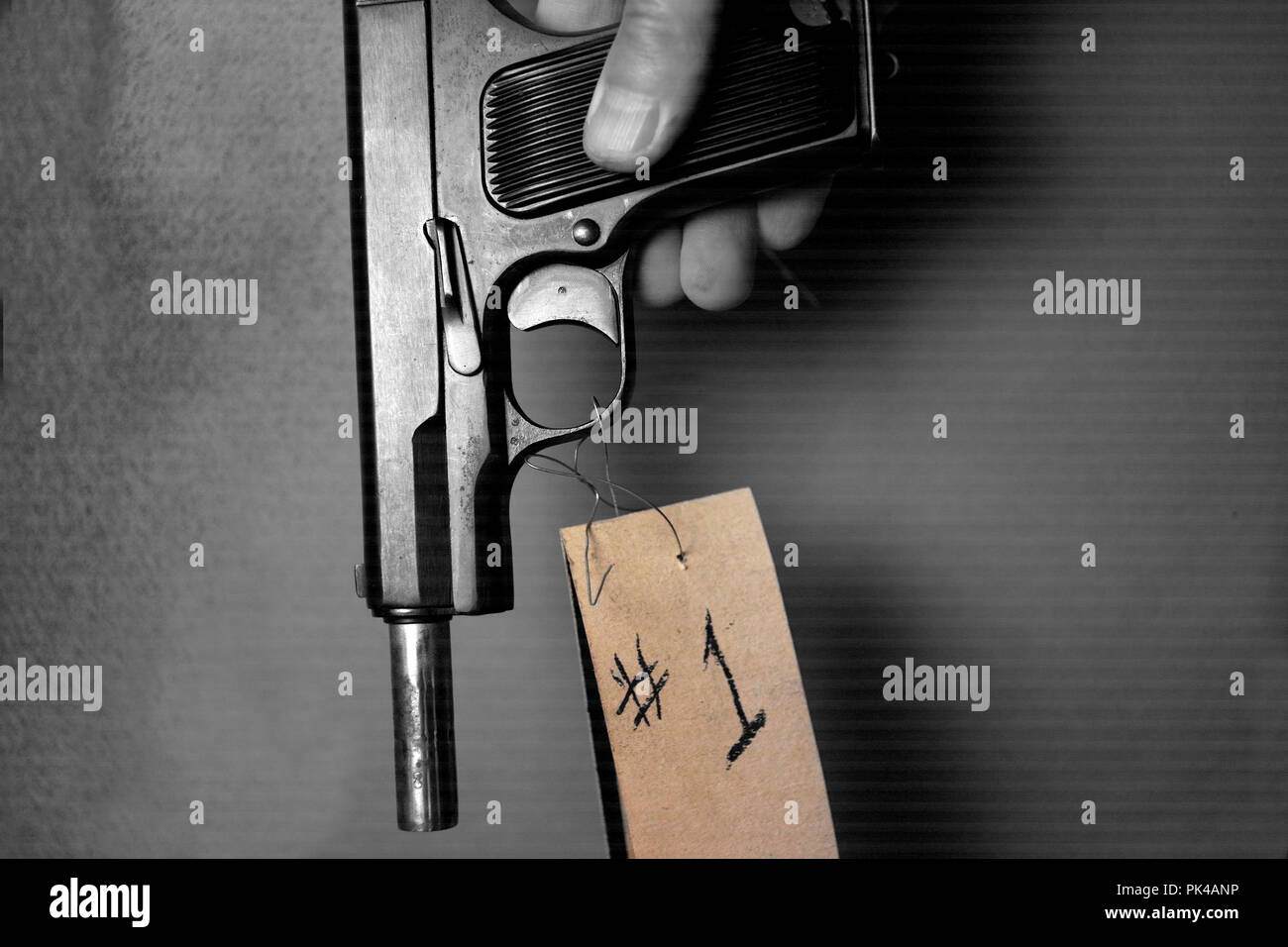 Human hand carefully holding a handgun tagged as a evidence, closeup ...
