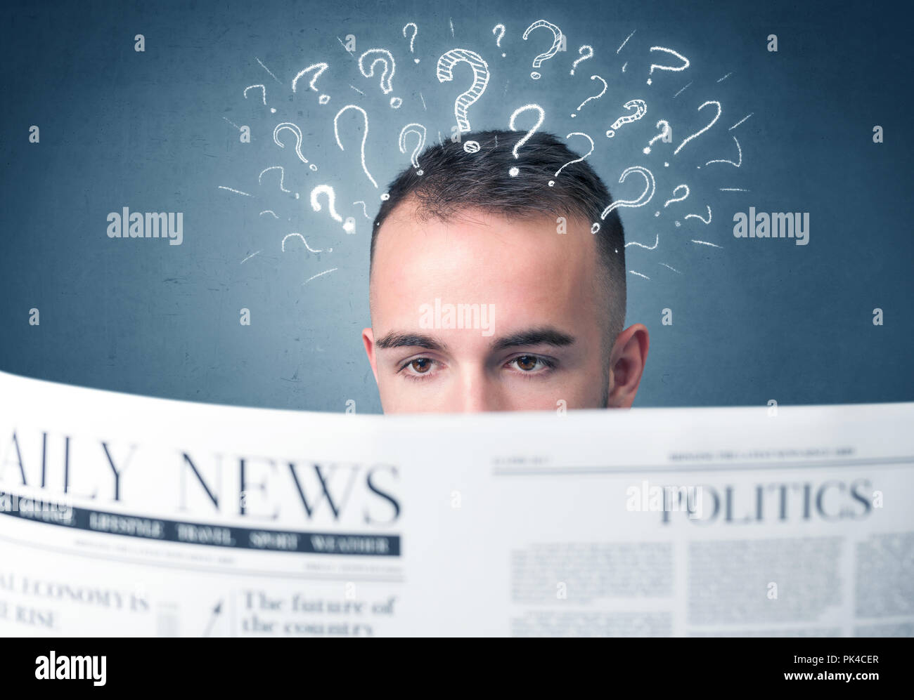 Young confused businessman reading daily newspaper with question marks ...