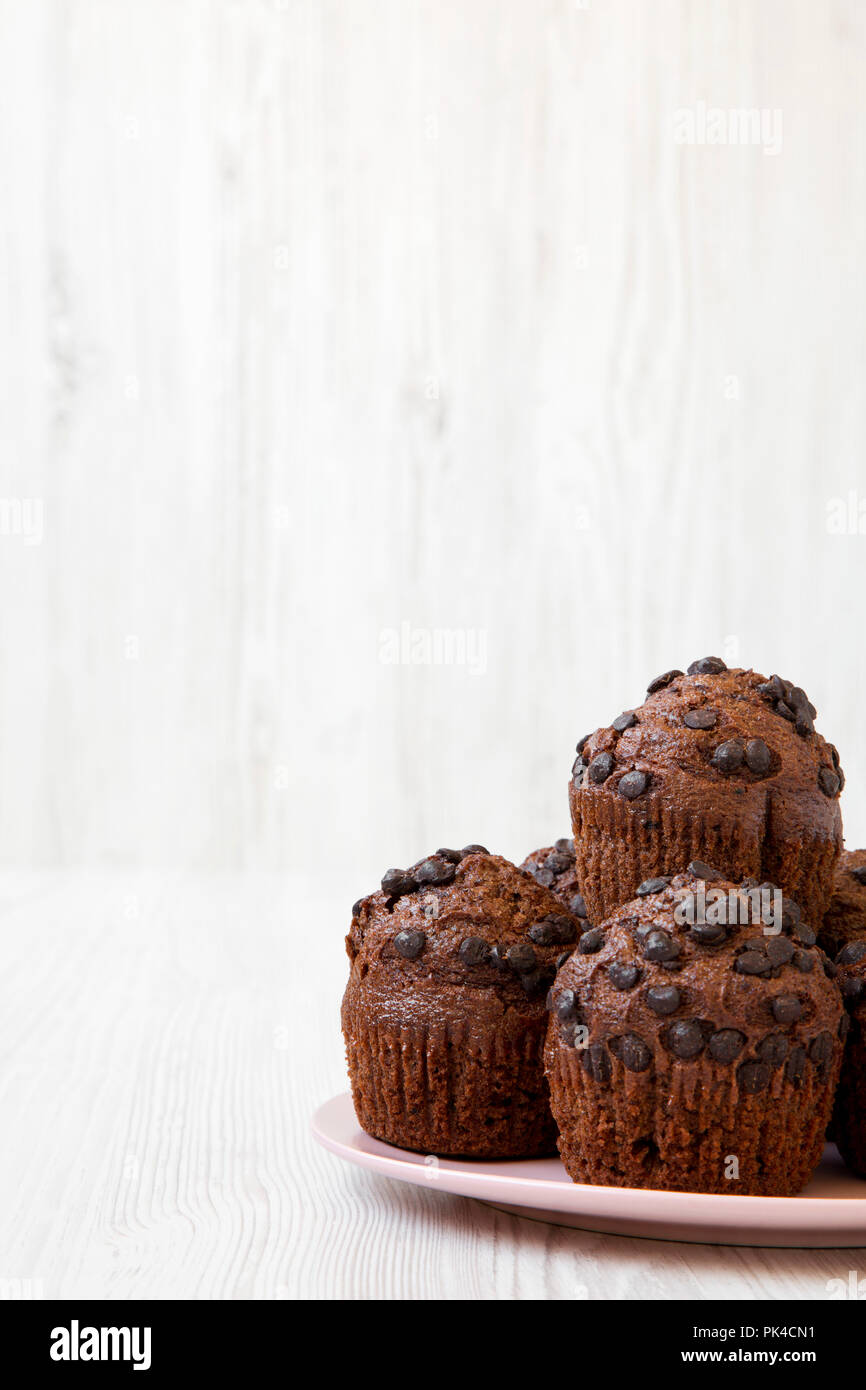 Chocolate cupcakes on pink plate on white wooden background, side view ...