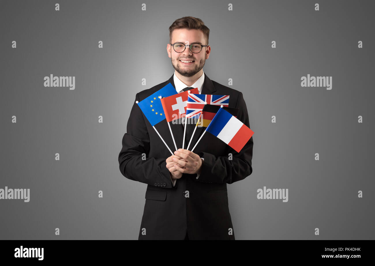 Cheerful student standing in front of wall with national flag on his ...