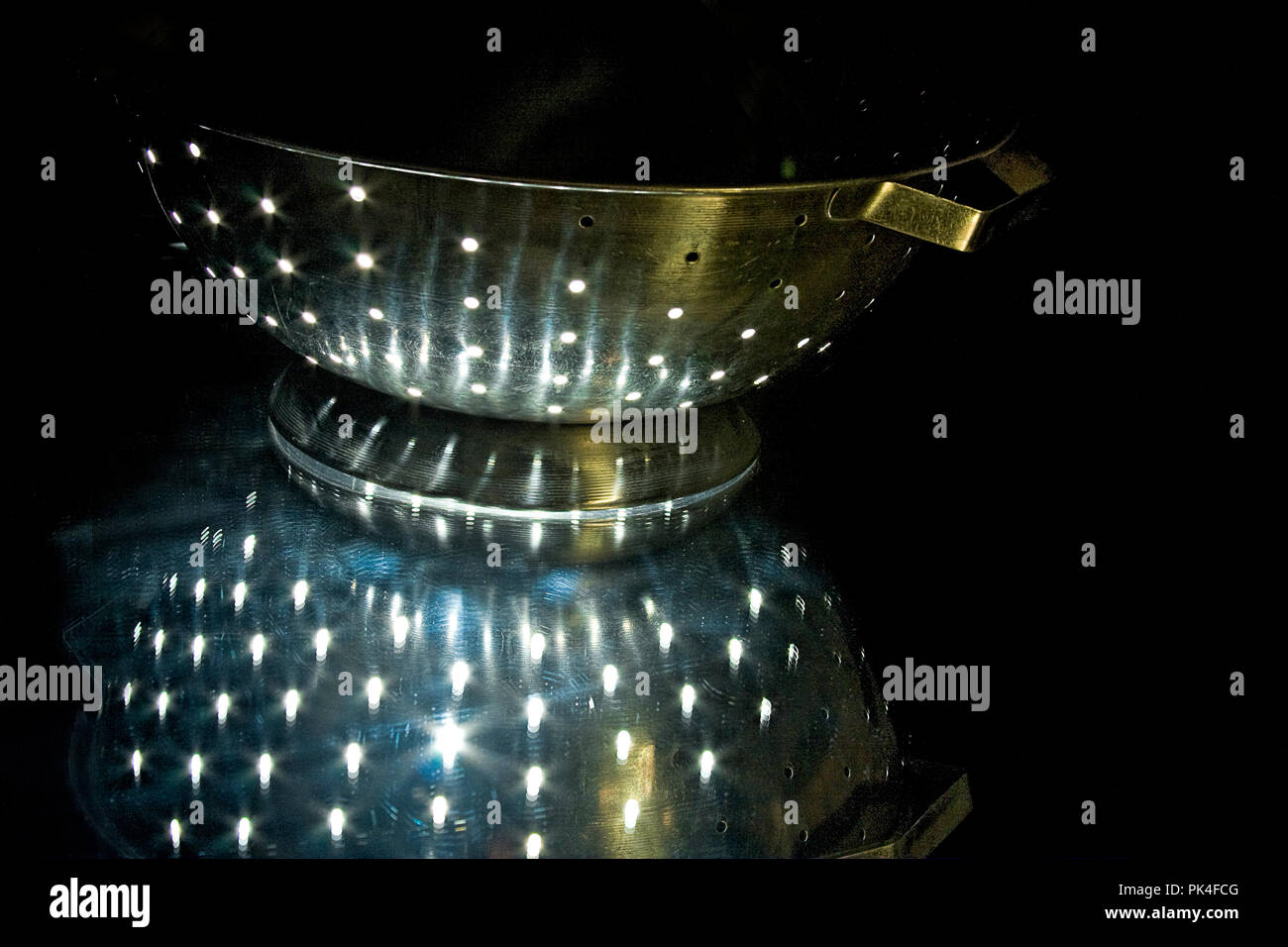 Unique image with a metal colander sitting on a counter at night with ...