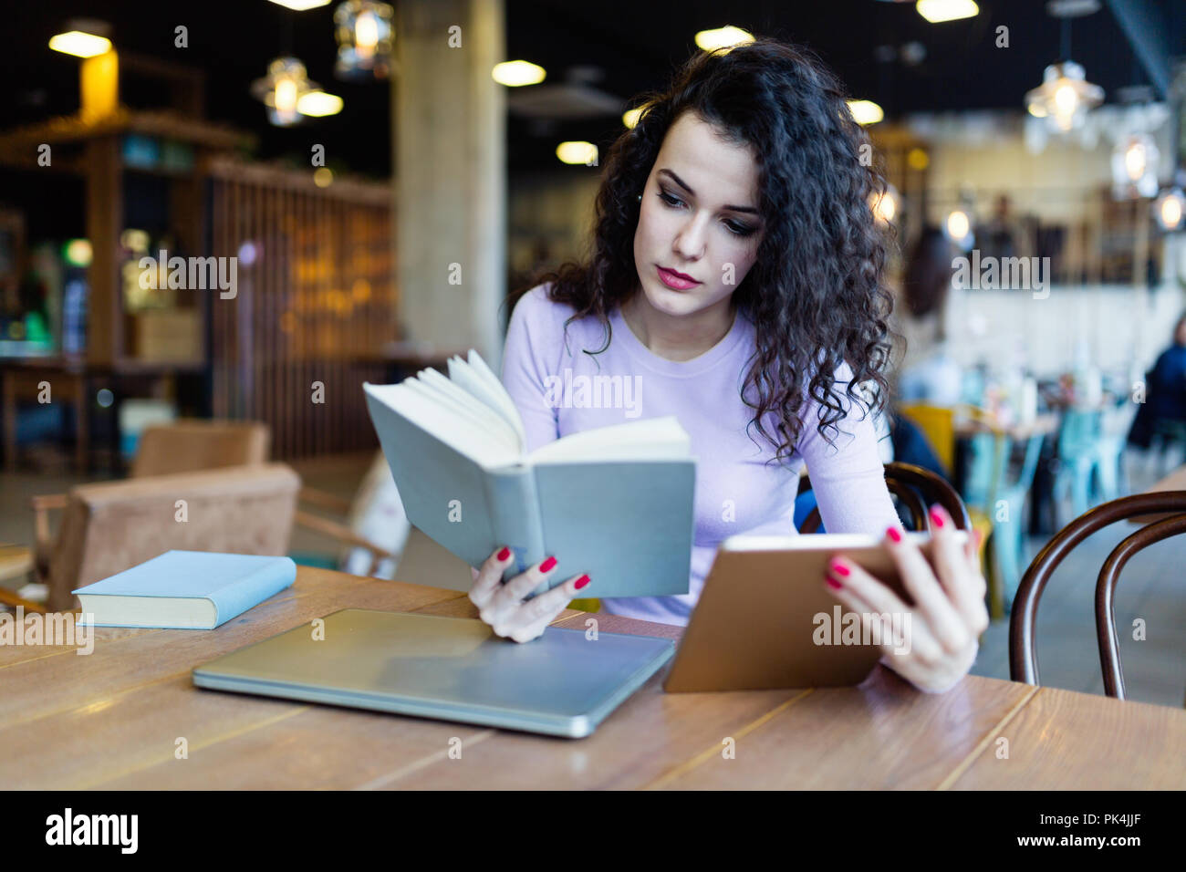 Young pretty girl reading book in coffee shop Stock Photo - Alamy