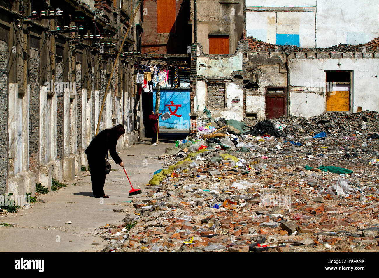 Sweeping the path among the rubble of demolished houses. Street life in ...