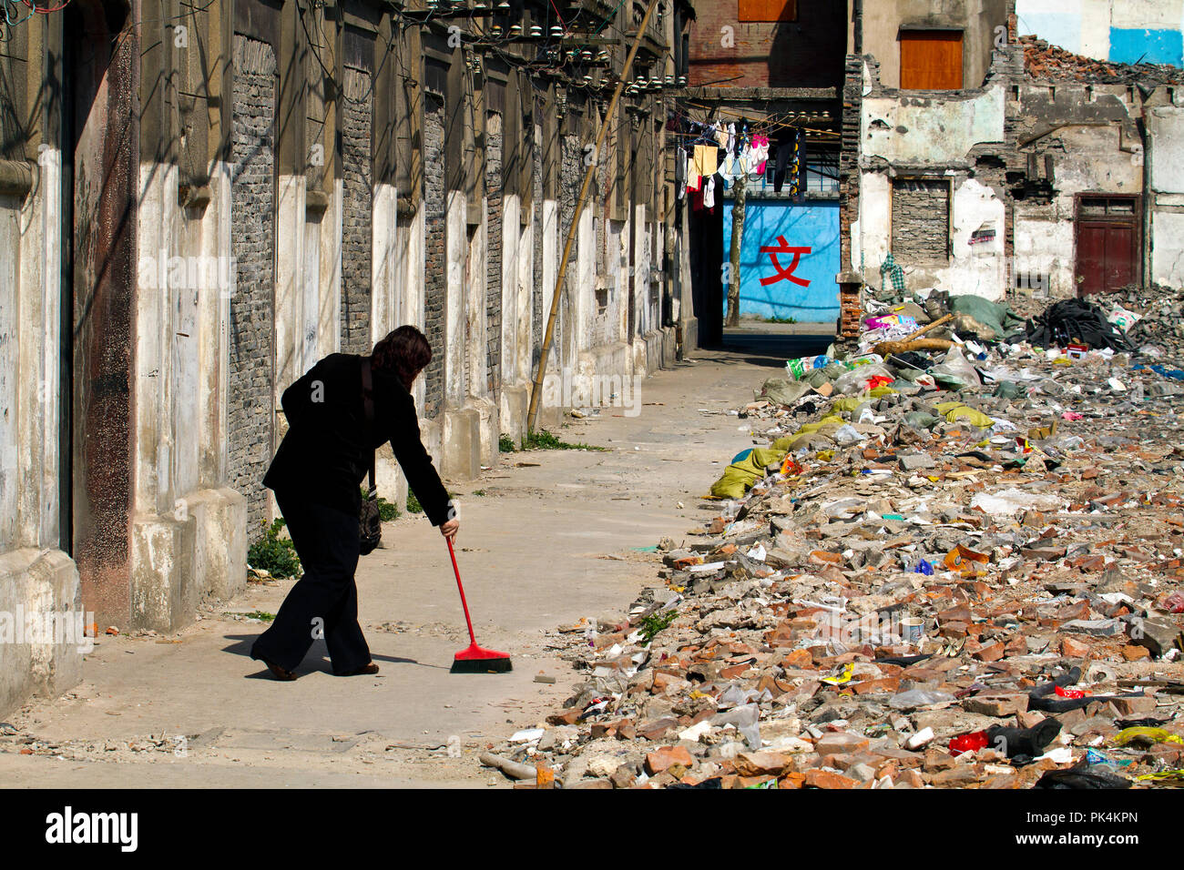 Sweeping the path among the rubble of demolished houses. Street life in ...