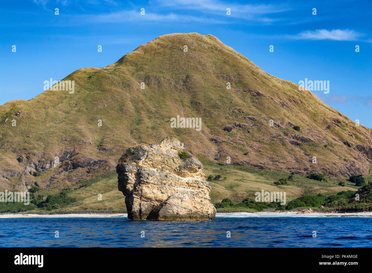 Rock formation rising out of the ocean near a beach on the Pulau Padar ...