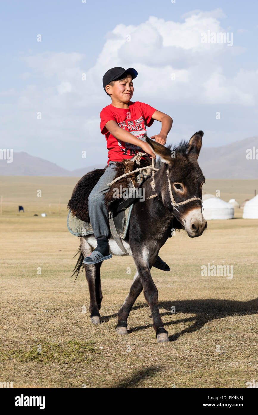 Song Kul, Kyrgyzstan, August 8 2018: A boy in a red T-shirt rides a ...