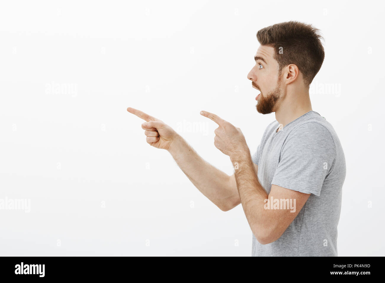 Studio shot of surprised and impressed handsome guy standing in profile ...