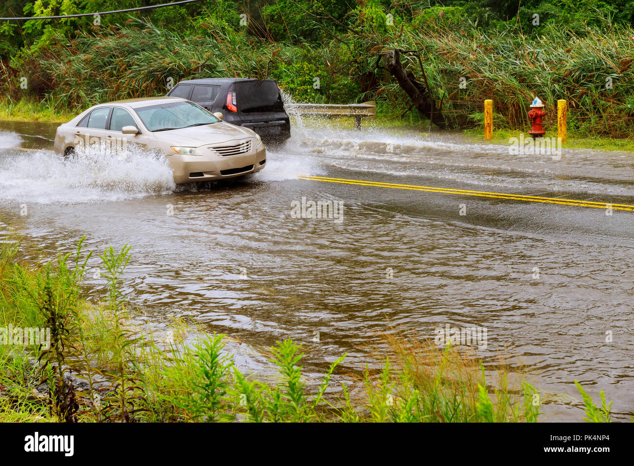 Splash by car as it goes through flood water after heavy rains of ...