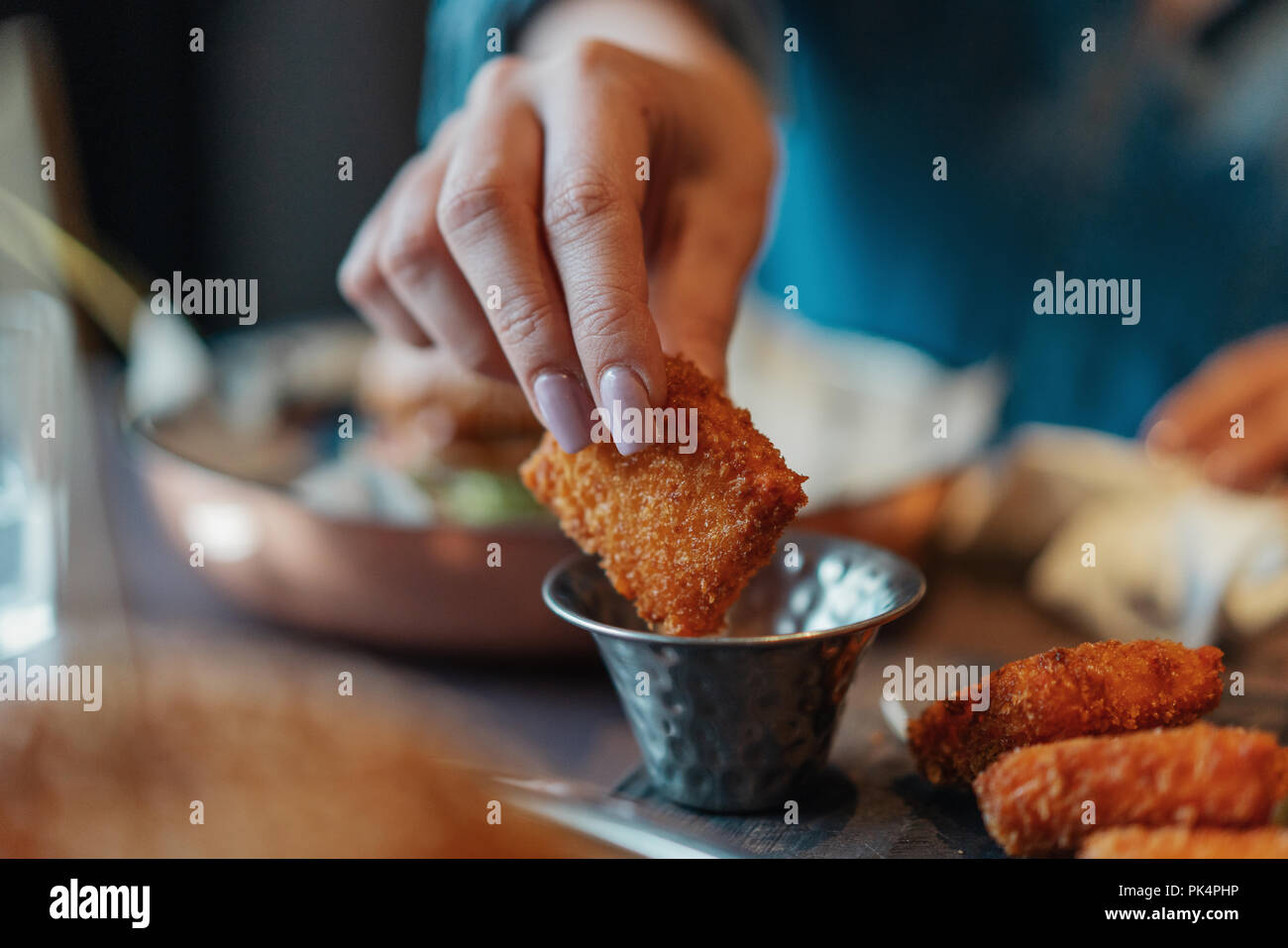 Close up of woman hands holding fried cheese and dipping it into a ...
