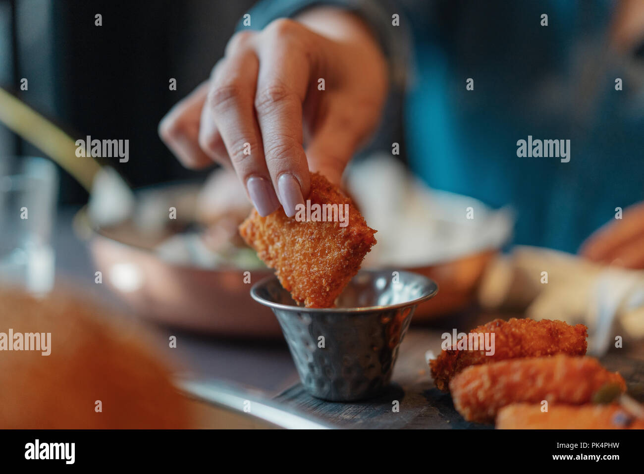 Close up of woman hands holding fried cheese and dipping it into a ...