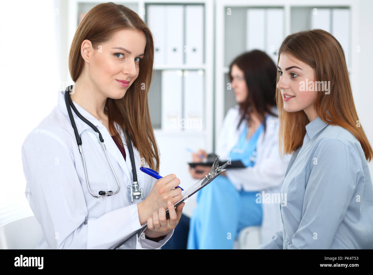 Young beautiful female doctor smiling while consulting her patient ...