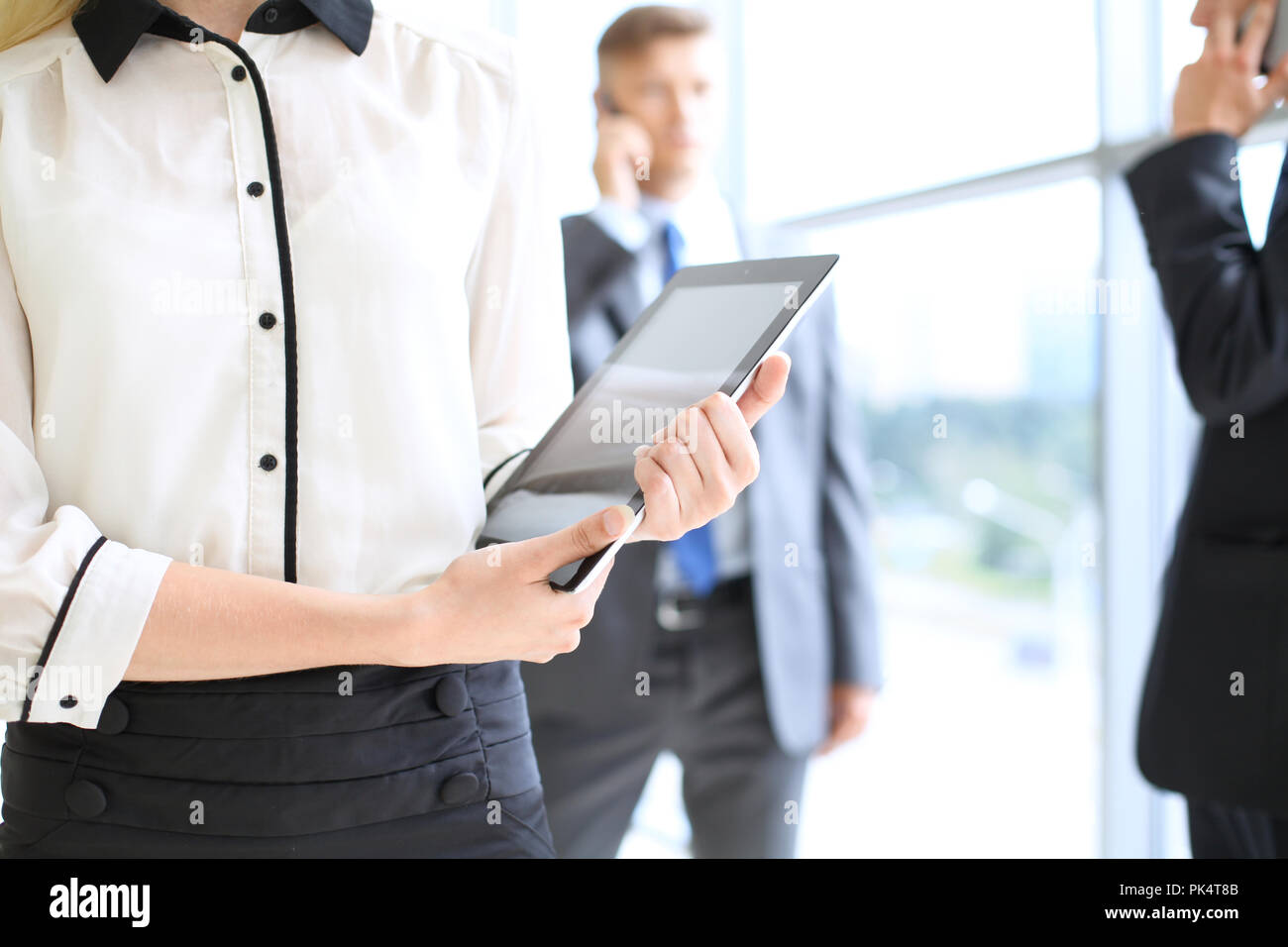 Unknown business woman using tablet computer in office hall among ...