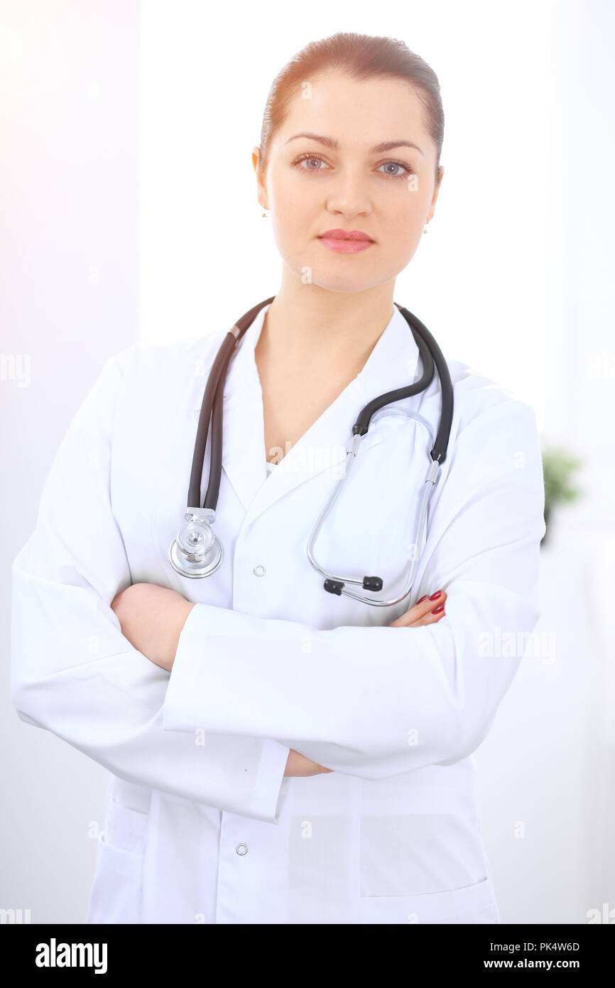 Brunette female doctor standing straight at hospital. Medicine and ...