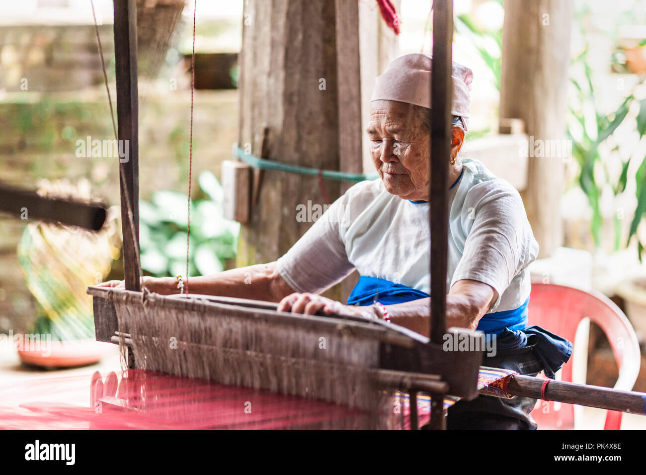 Local woman diligently working at a loom, weaving colourful brocade ...