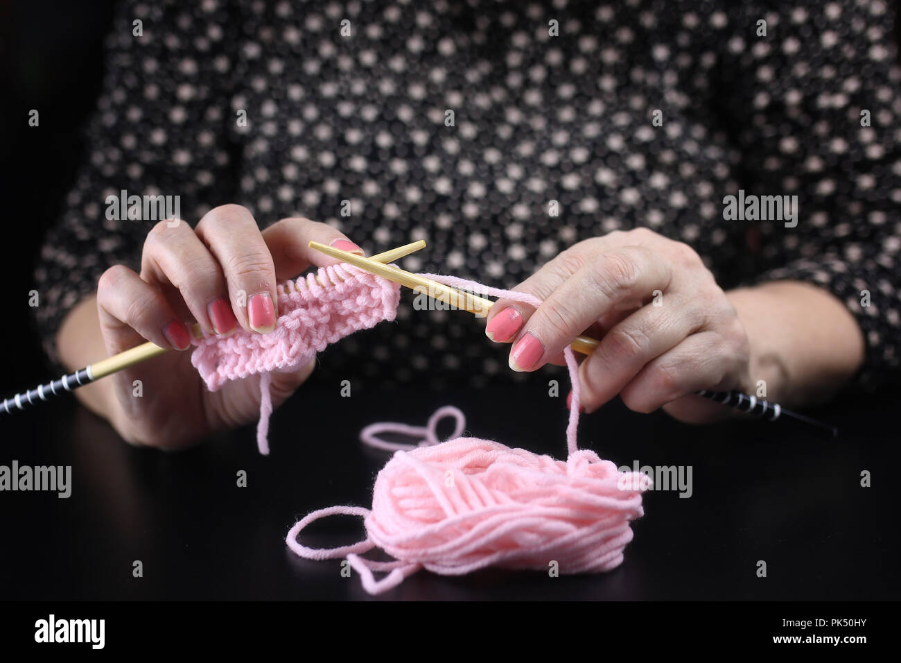elderly woman is engaged in knitting warm sweaters for her grand Stock ...
