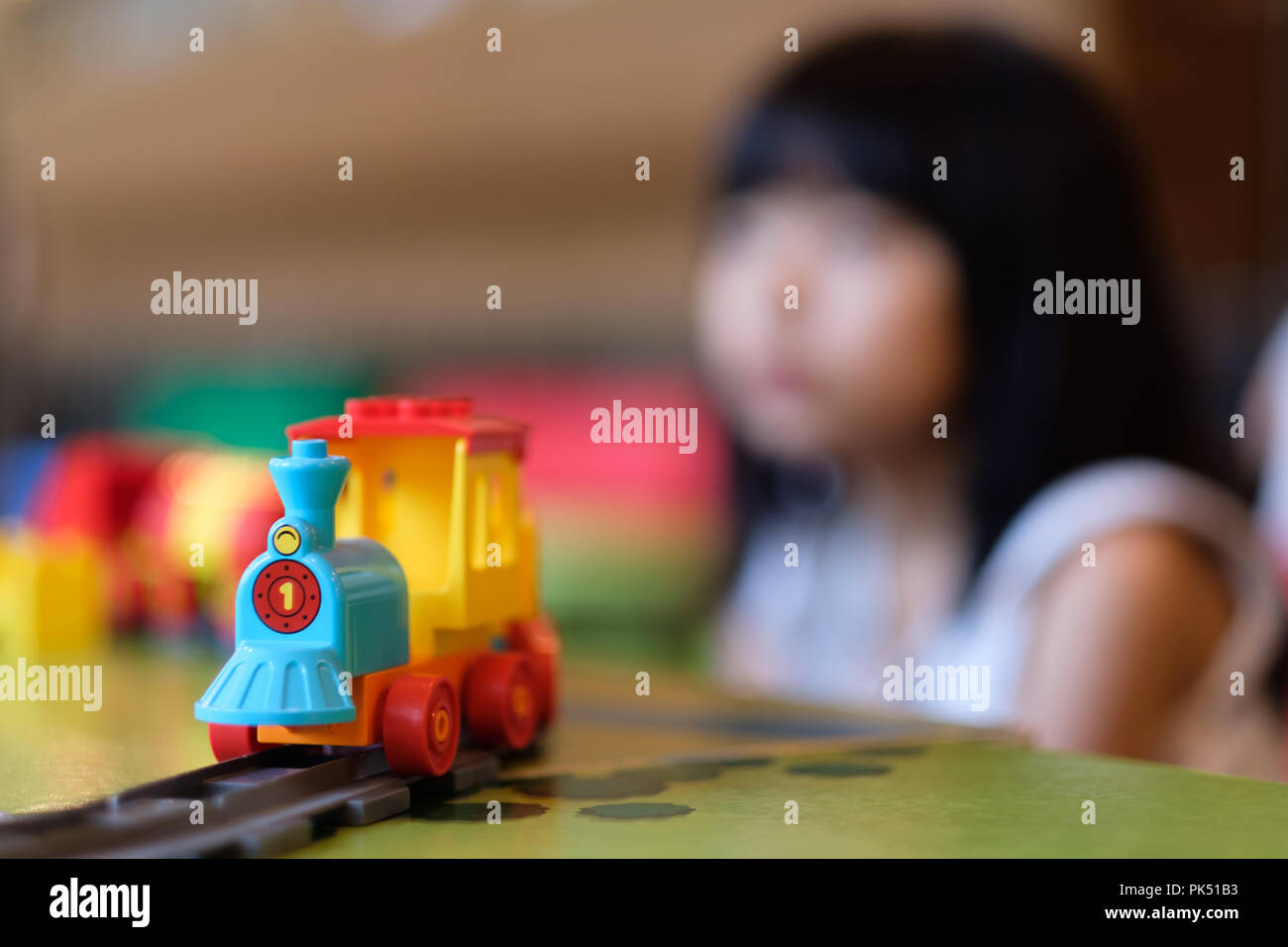 Little girl kid playing with train toy Stock Photo - Alamy