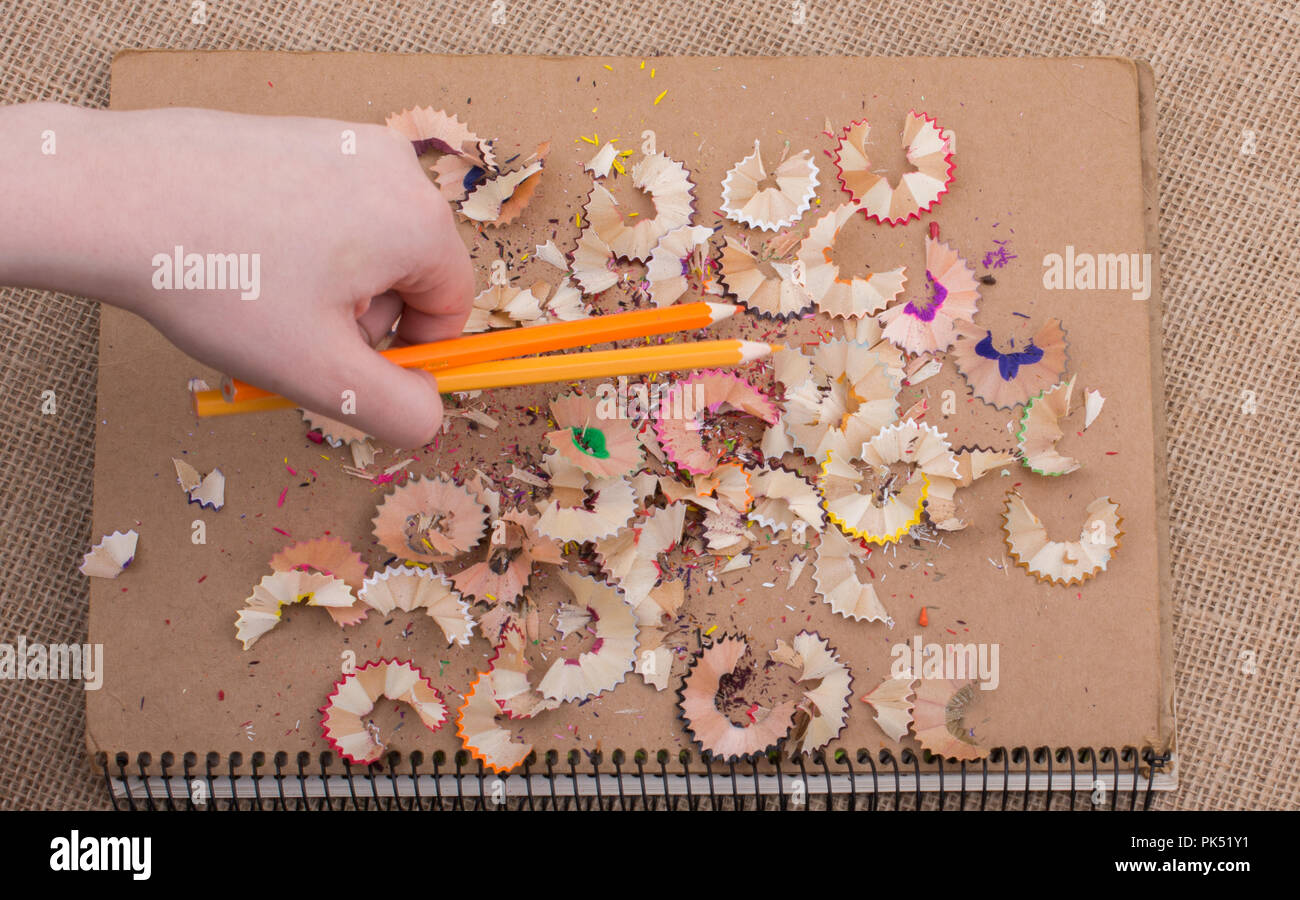 Hand holding Color Pencils over a notebook with pencil shavings Stock ...