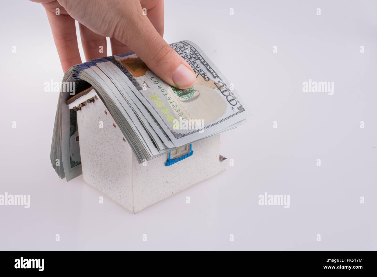 Hand holding American dollar banknotes on the roof of a model house on ...