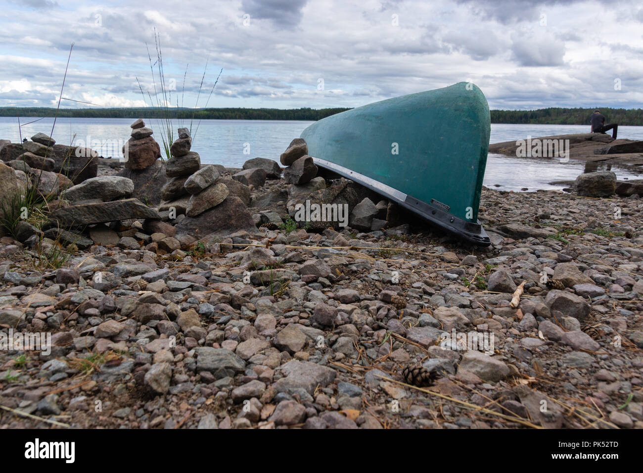 Canoe lies at a stony beach in front of a lake Stock Photo - Alamy
