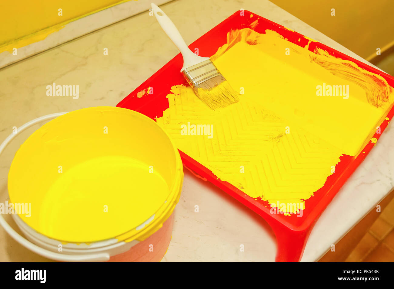 Bucket with yellow color and the brush ready for painting the wall ...
