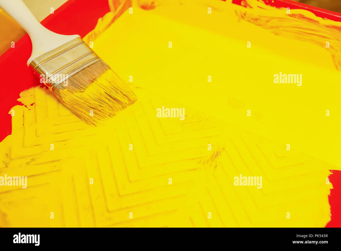 Bucket with yellow color and the brush ready for painting the wall ...