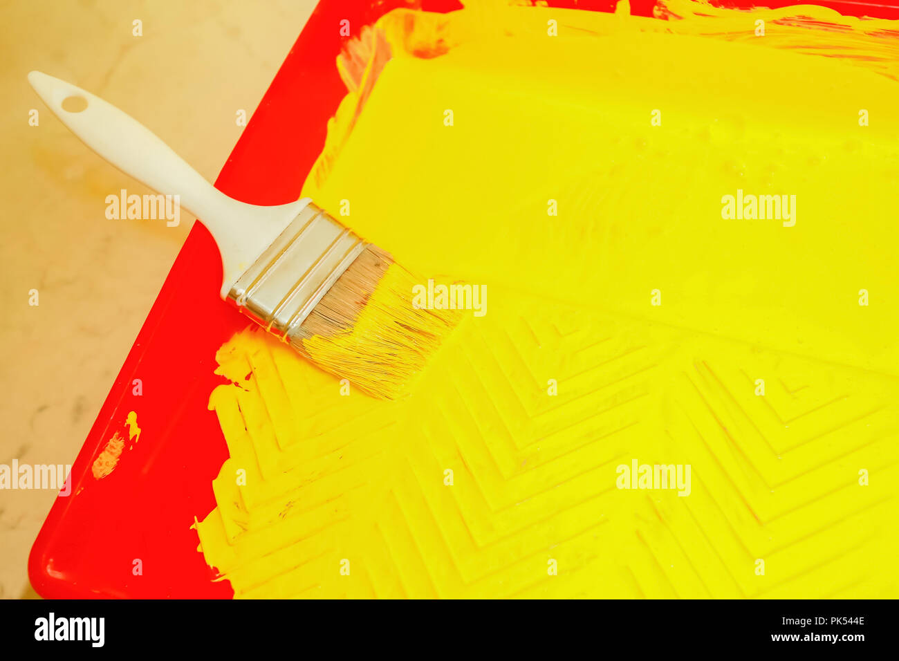 Bucket with yellow color and the brush ready for painting the wall ...