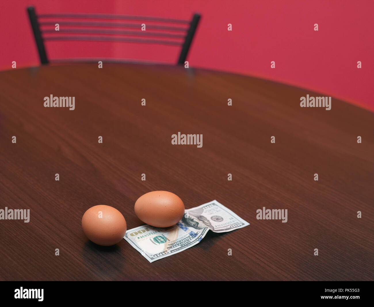 Two chicken eggs and a dollar banknote laid ona table top, concept of ...