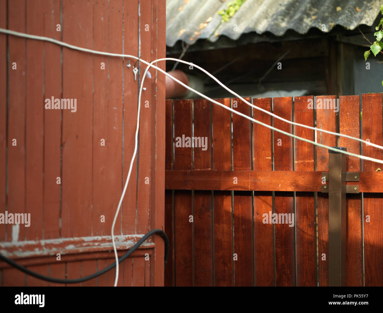 Hanging low electric cables attachred to a wall and fence Stock Photo ...