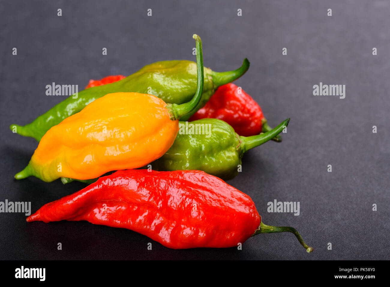 A heap of various colours ghost pepper on a dark surface Stock Photo ...
