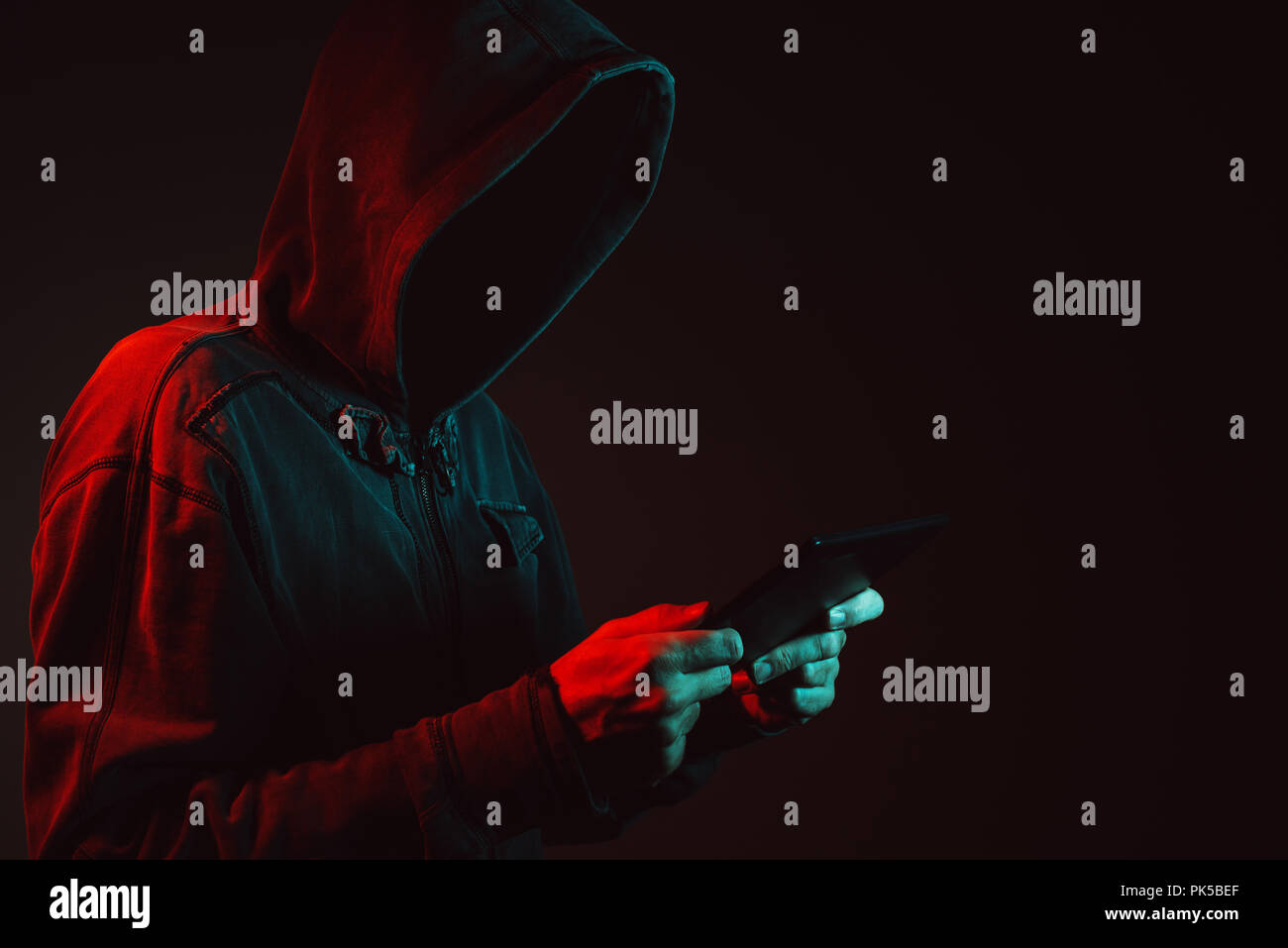 Hooded Faceless Hacker With Tablet Computer In Cybersecurity Concept
