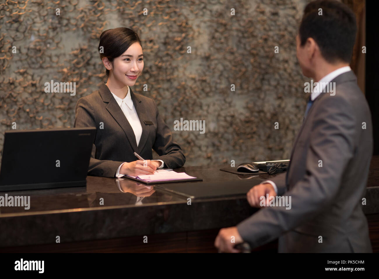 Cheerful businessman checking into hotel Stock Photo - Alamy