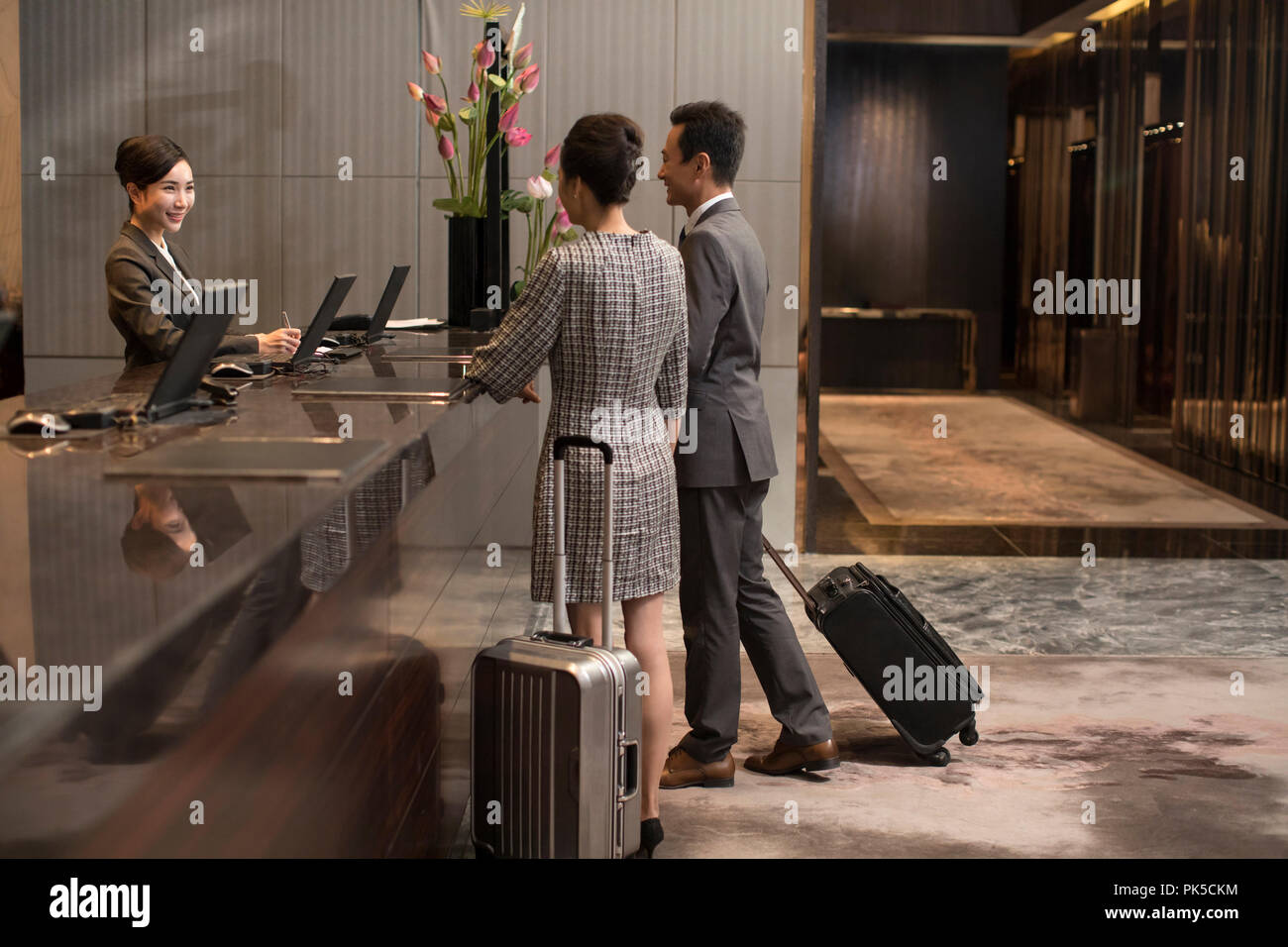 Couple checking into hotel Stock Photo - Alamy