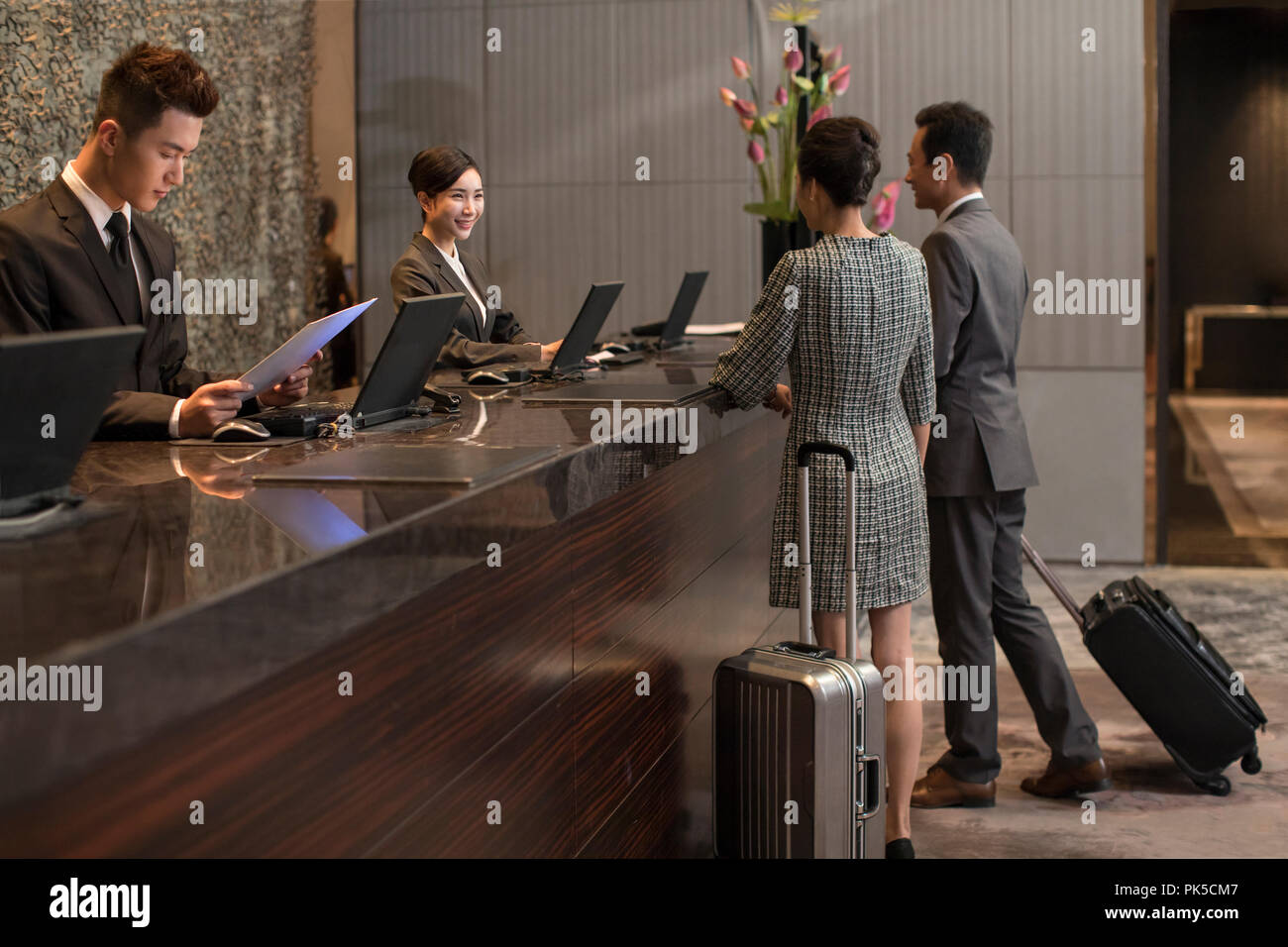 Couple checking into hotel Stock Photo - Alamy