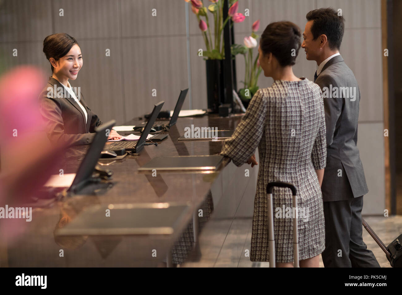 Couple checking into hotel Stock Photo - Alamy