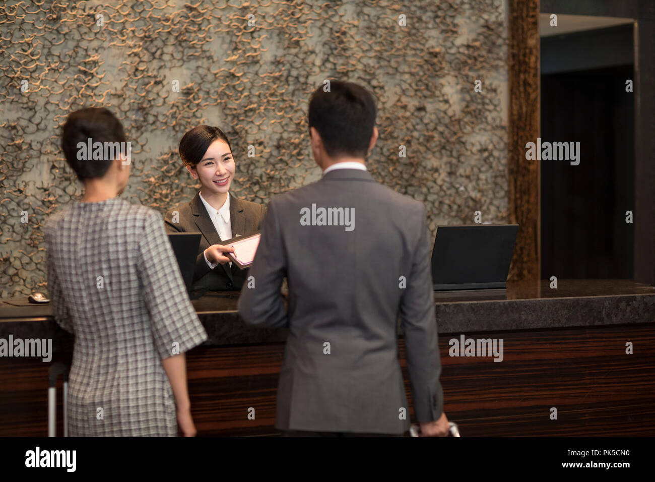 Couple checking into hotel Stock Photo - Alamy