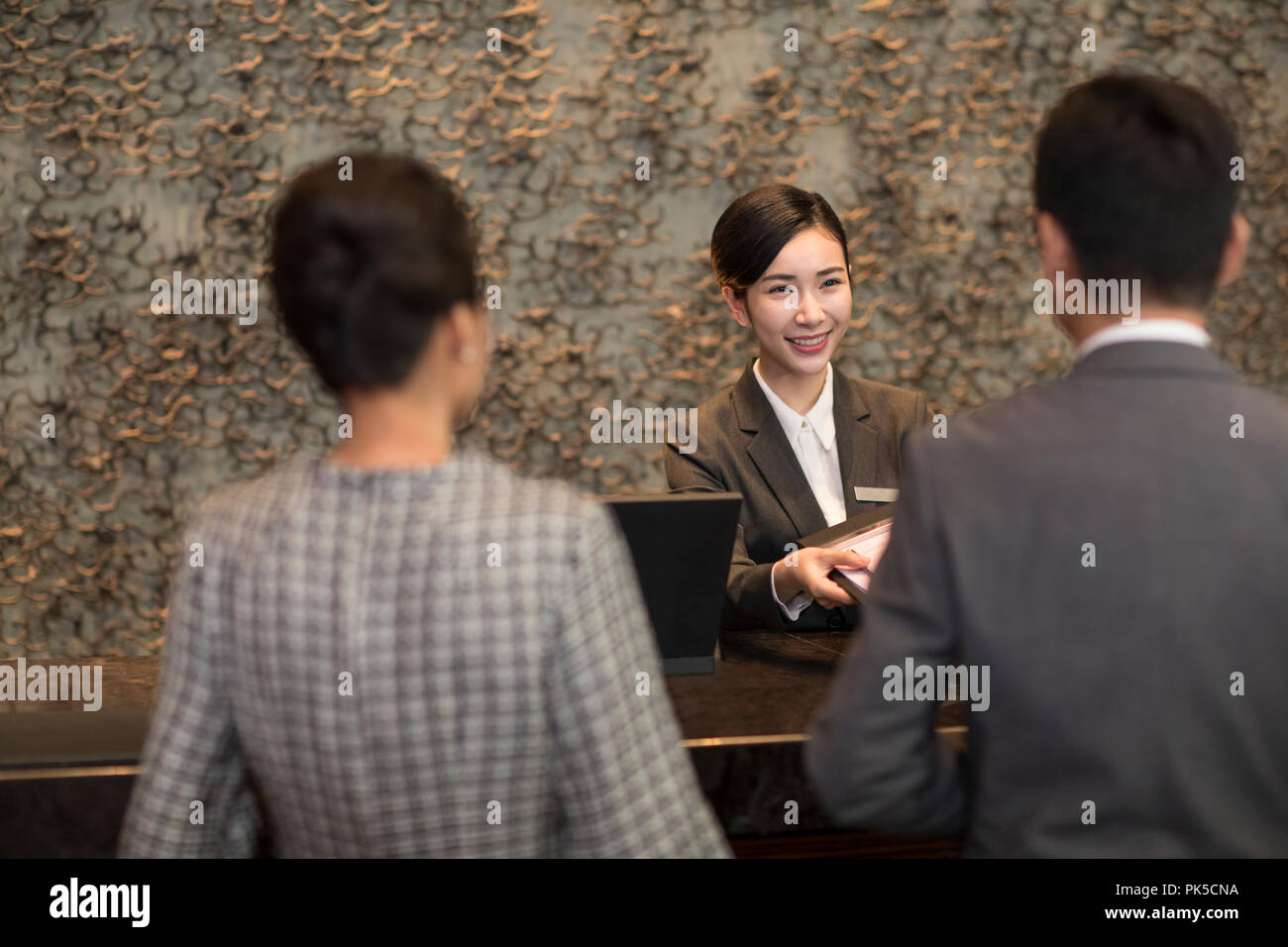 Couple checking into hotel Stock Photo - Alamy