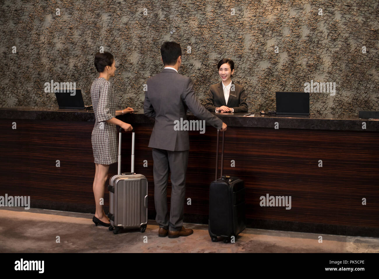 Couple checking into hotel Stock Photo - Alamy