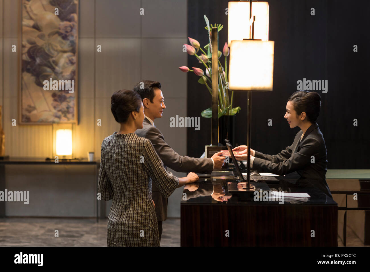 Couple checking into hotel Stock Photo - Alamy