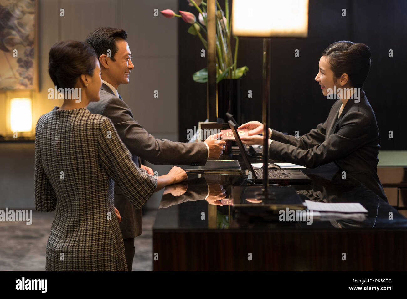 Couple checking into hotel Stock Photo - Alamy