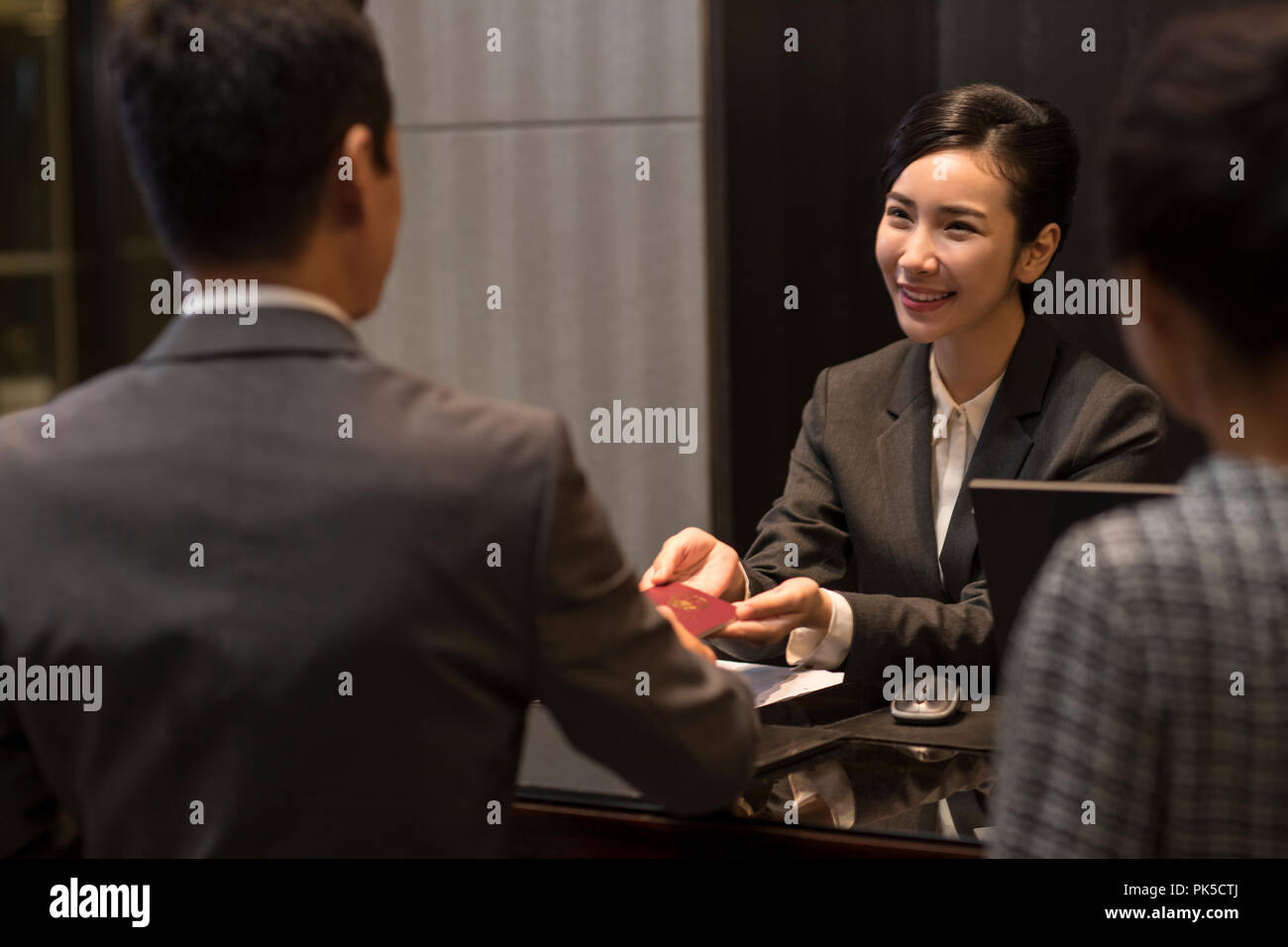 Couple checking into hotel Stock Photo - Alamy