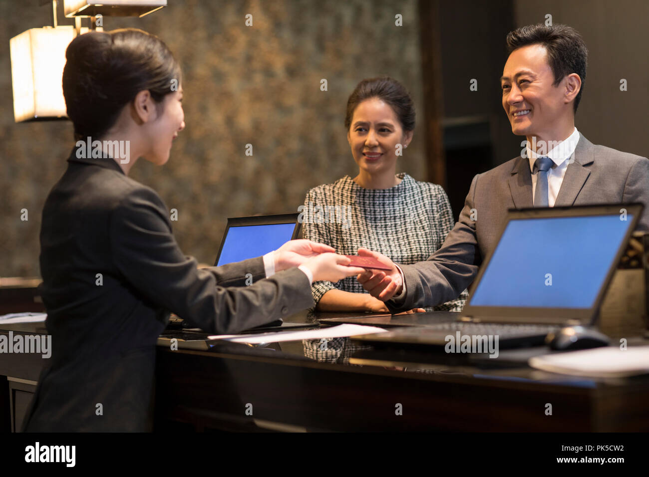 Couple checking into hotel Stock Photo - Alamy