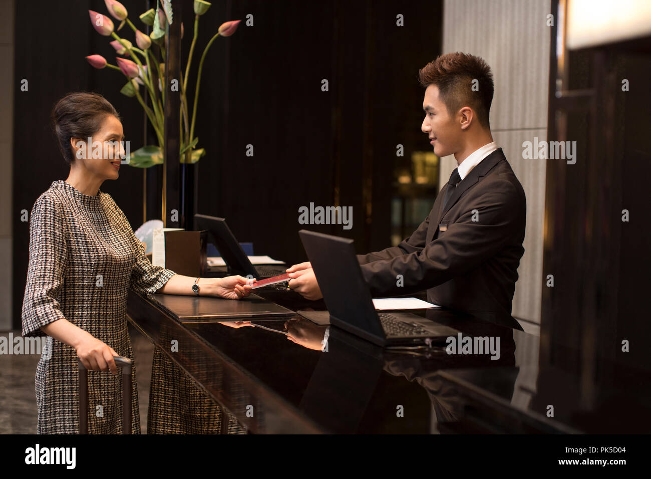 Elegant woman checking into hotel Stock Photo - Alamy