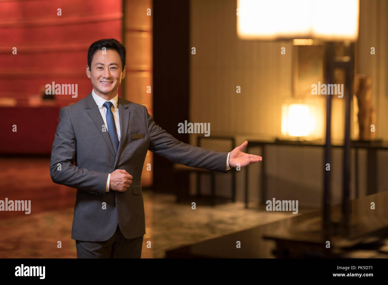 Confident hotel manager greeting Stock Photo - Alamy