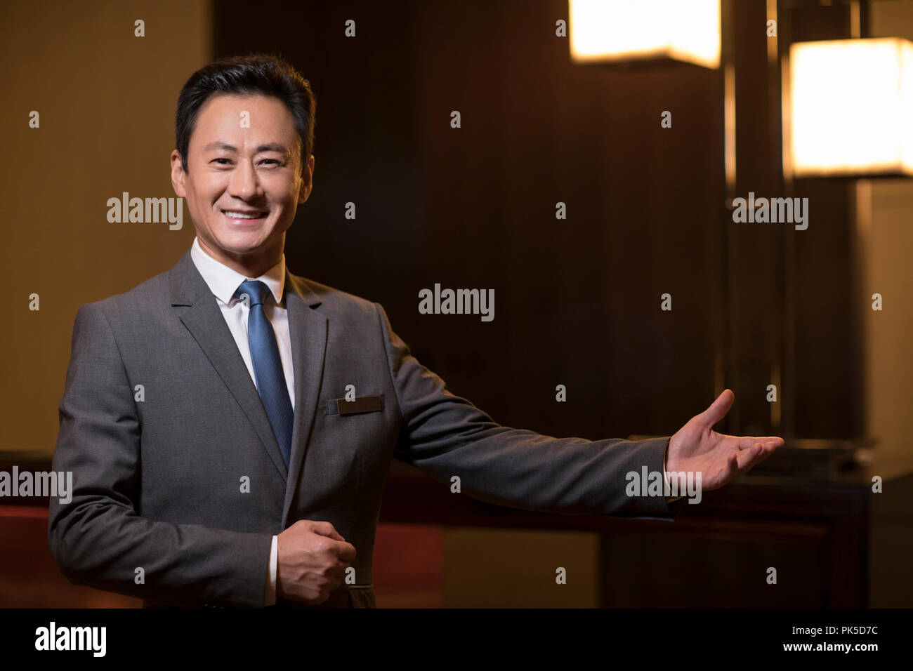 Confident hotel manager greeting Stock Photo - Alamy