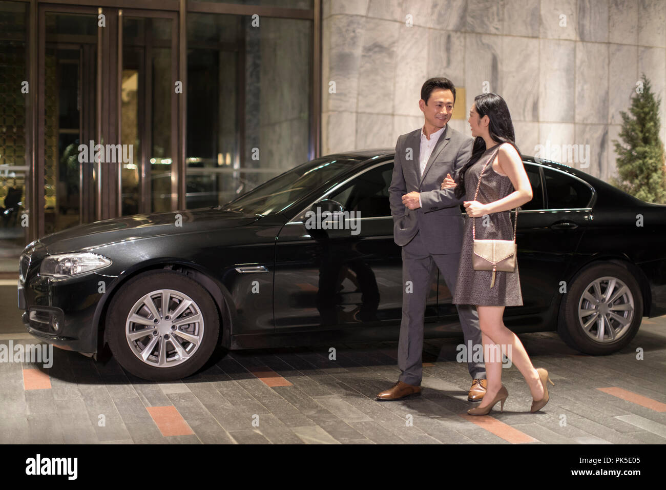 Cheerful young couple arriving at hotel by car Stock Photo - Alamy