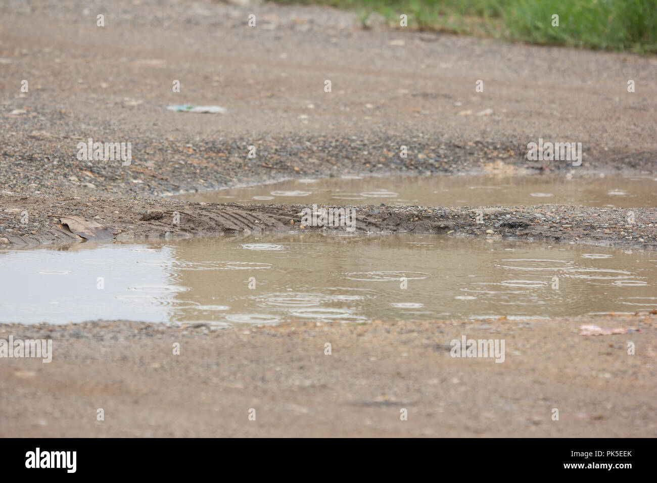water puddles with raindrops and water circles on cracked wet road ...